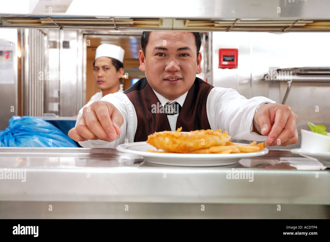 waiter picking up a plate with food in the galley onboard Queen Mary 2 ...