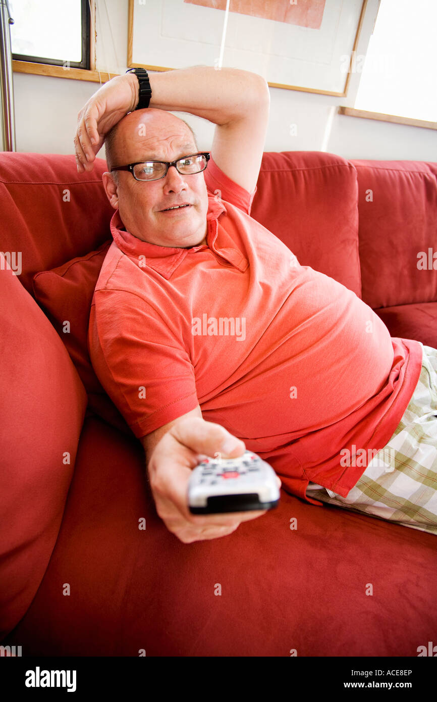 Man watching television on sofa Stock Photo - Alamy