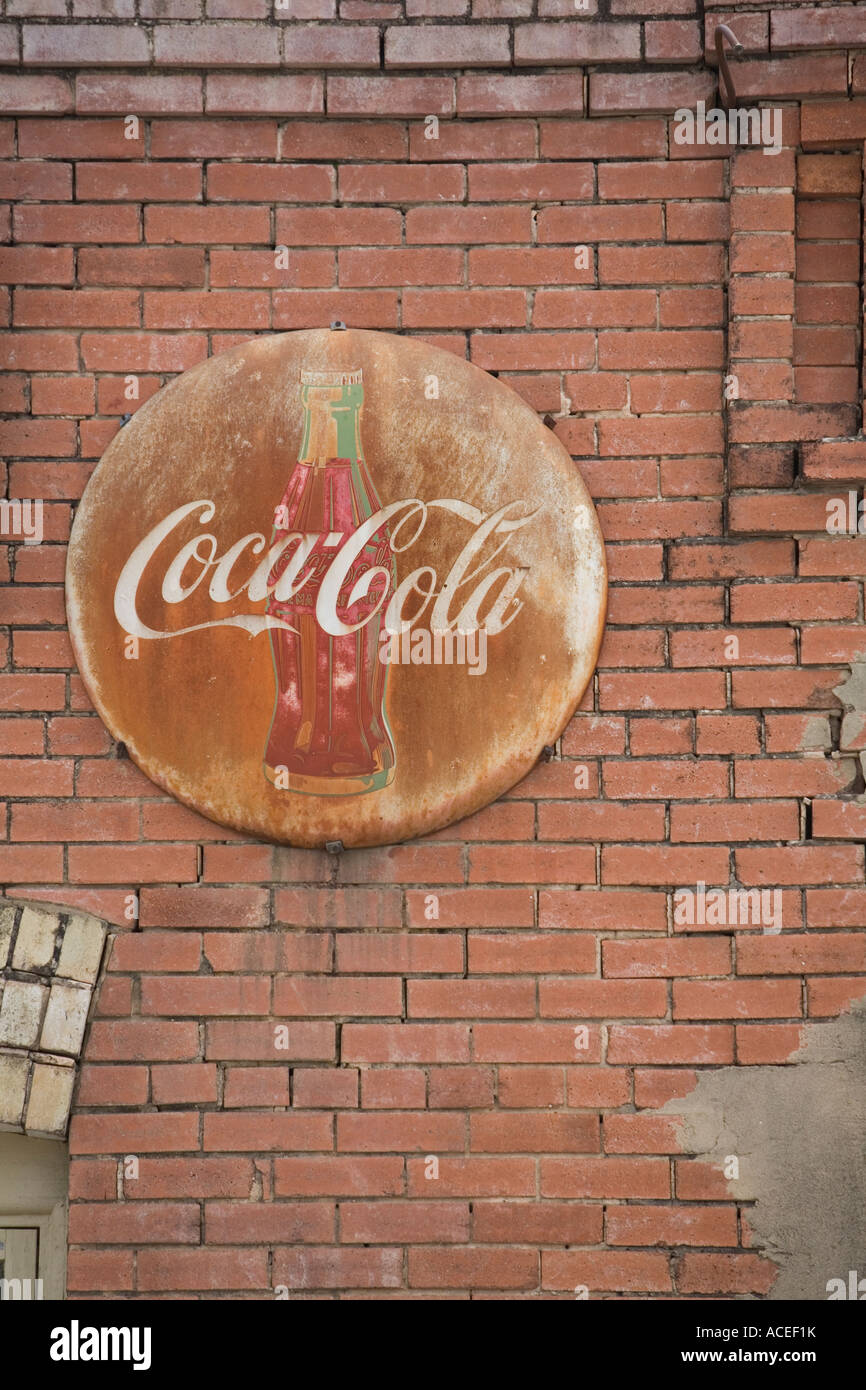 Coca Cola round sign on old building faded brick and rusted steel ...