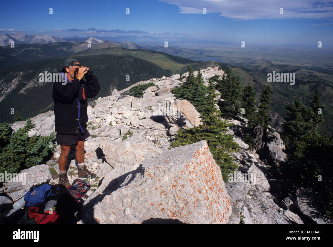 A hiker looking through binoculars from Heart Butte peak along the ...