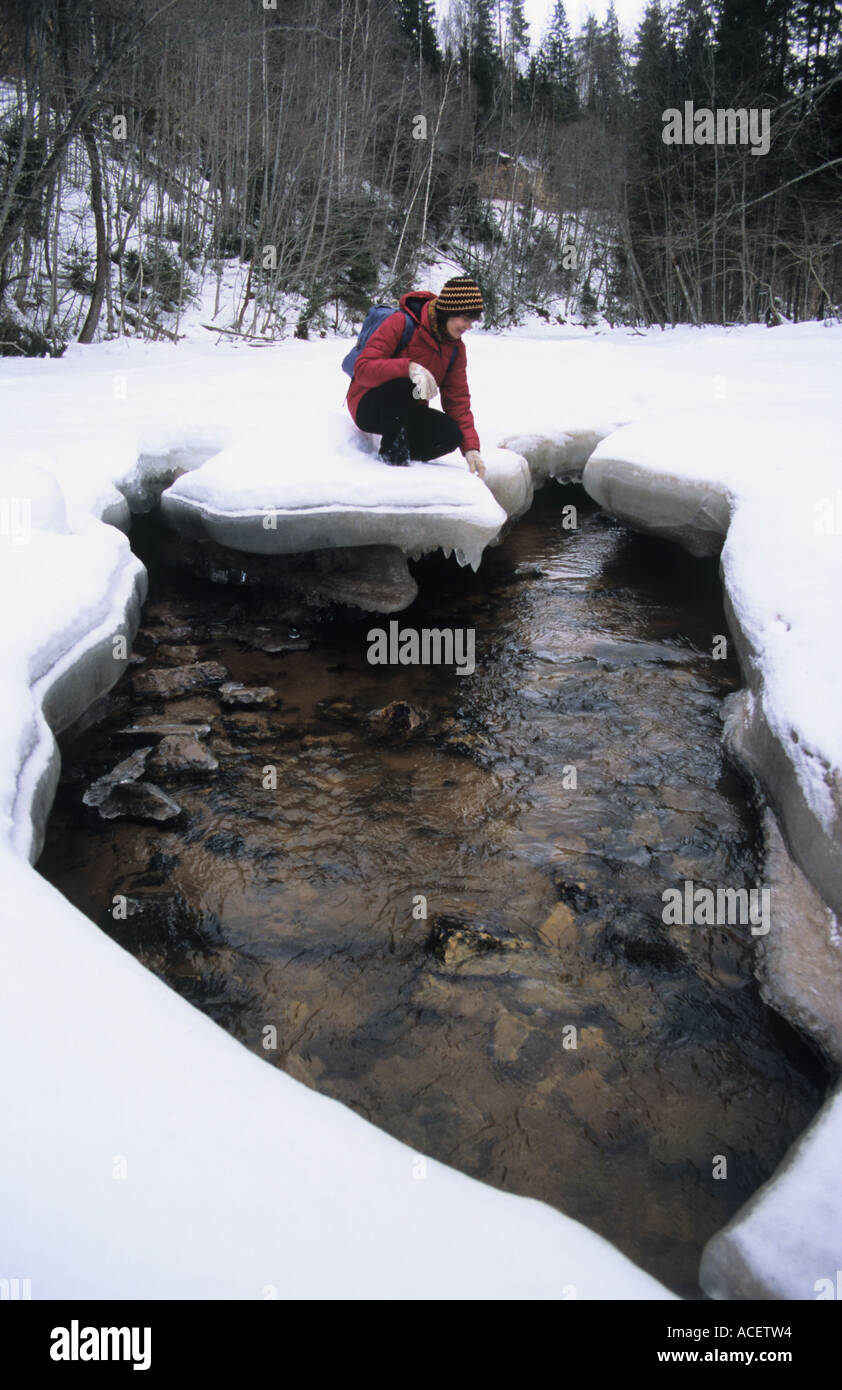Woman exploring ice hole on Amata river Karli surroundings Gauja ...