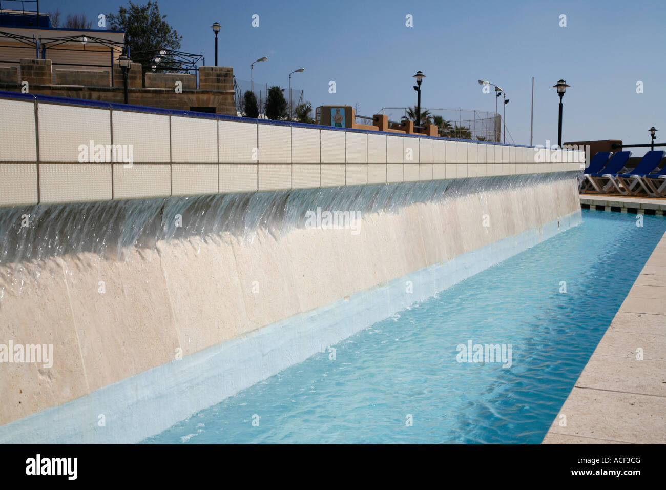 Water cascading over the edge of a swimming pool into a collection ...