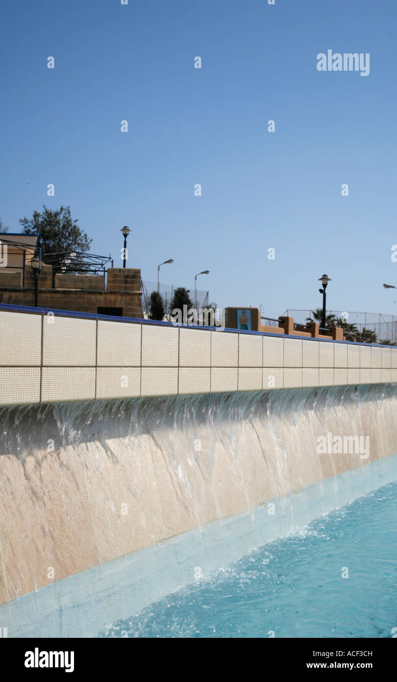 Water cascading over the edge of a swimming pool into a collection ...