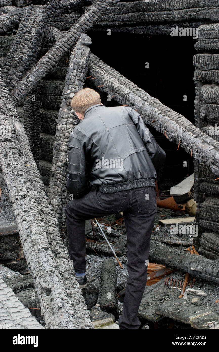 Man investigating fire damages at a burned down log cabin , Finland ...