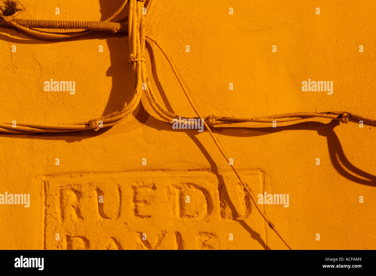 Cabling on a white wall lit yellow by street lighting, in Montpellier ...
