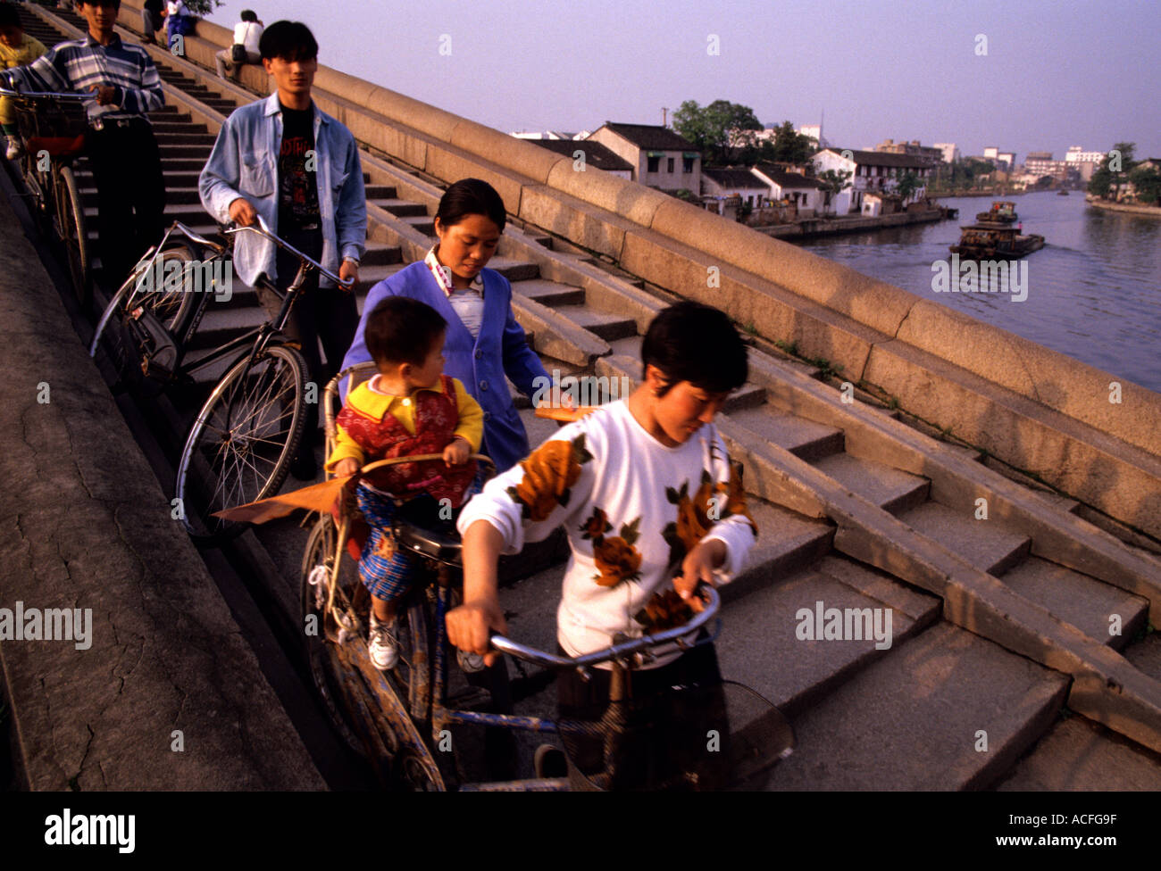 Suzhou Jiangsu China Bicycle riders walking their bikes over an arched ...