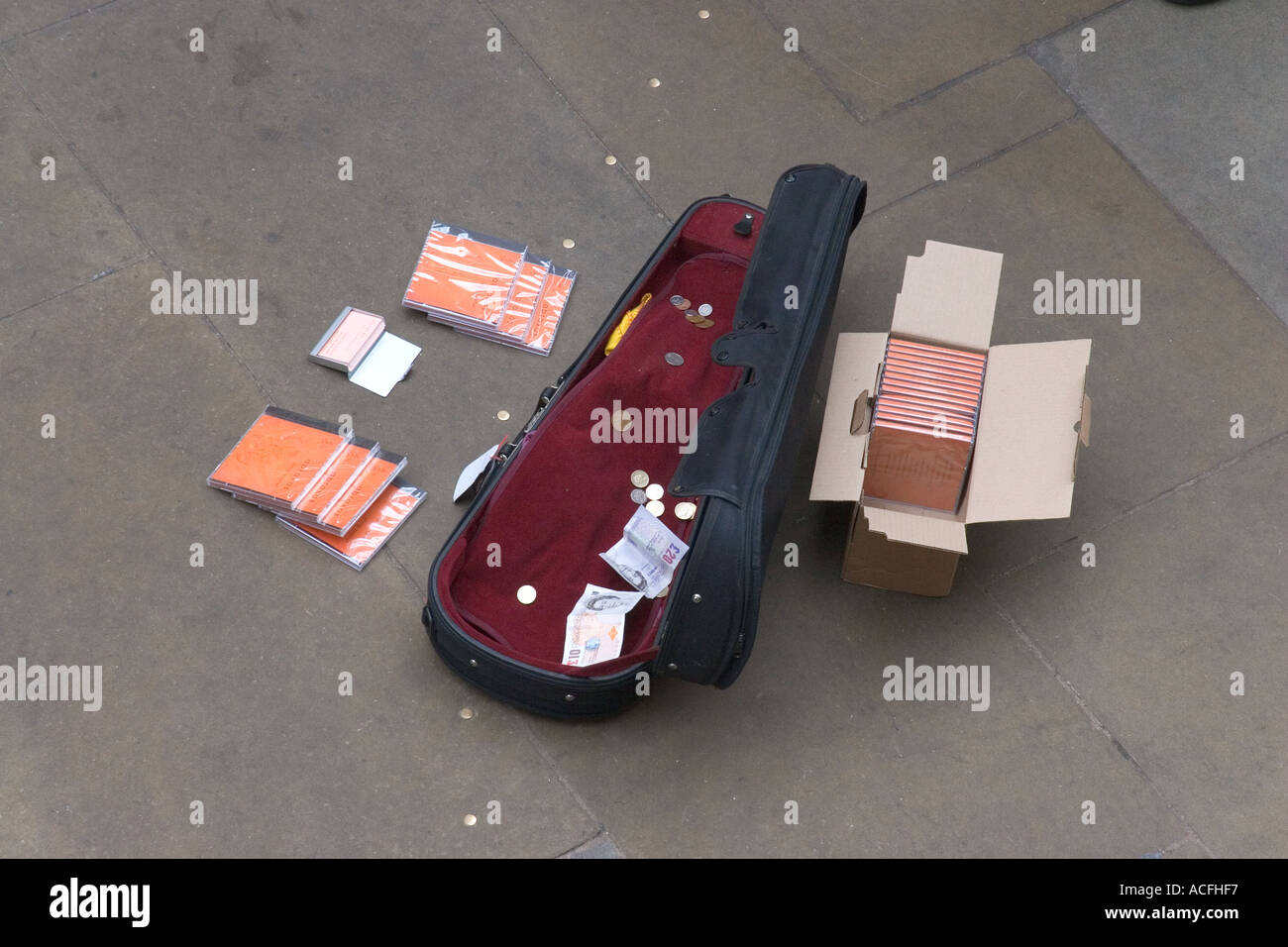Violin case openon the ground with money earned from busking and boxes ...