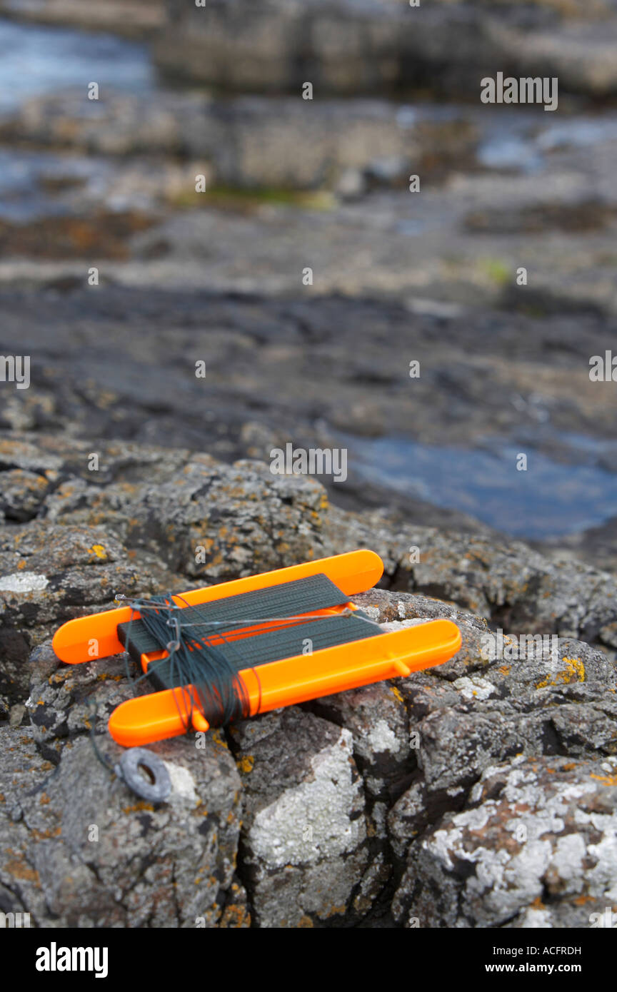 childrens bright orange crab line fishing line sitting on rocks with ...