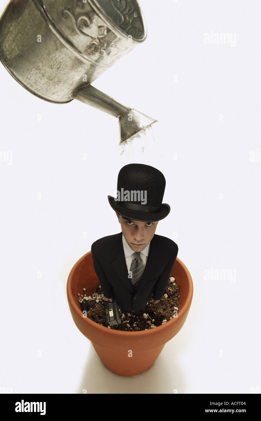 Man wearing suit in flower pot about to be watered Stock Photo - Alamy
