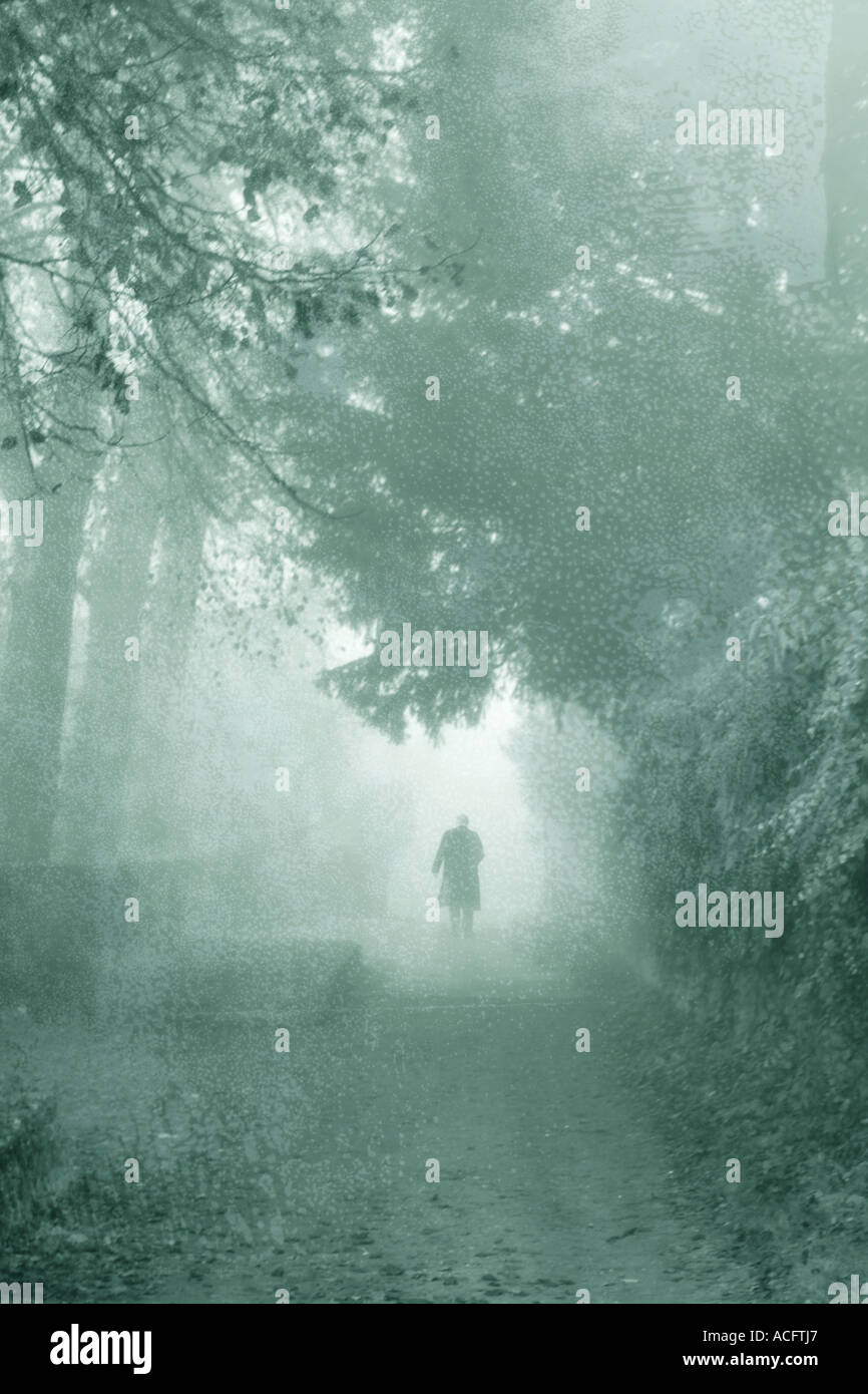photo of a man walking down a path in the mist Stock Photo - Alamy