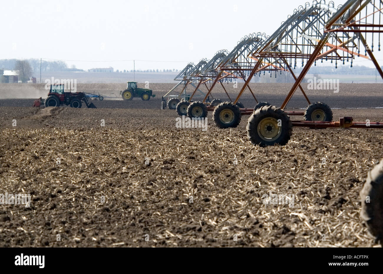 Irrigation system in the foreground with tractors in the background on ...