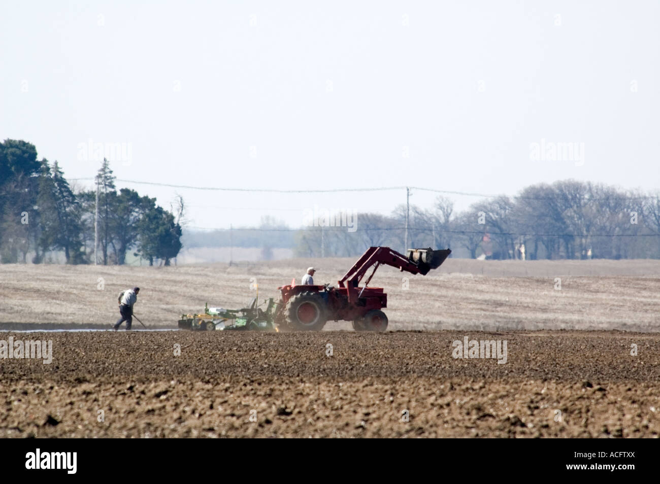 Farmer and helper put down a plastic barrier before planting sweet corn ...