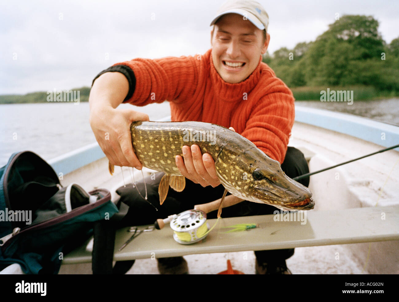 A man in a boat holding a pike Stock Photo - Alamy