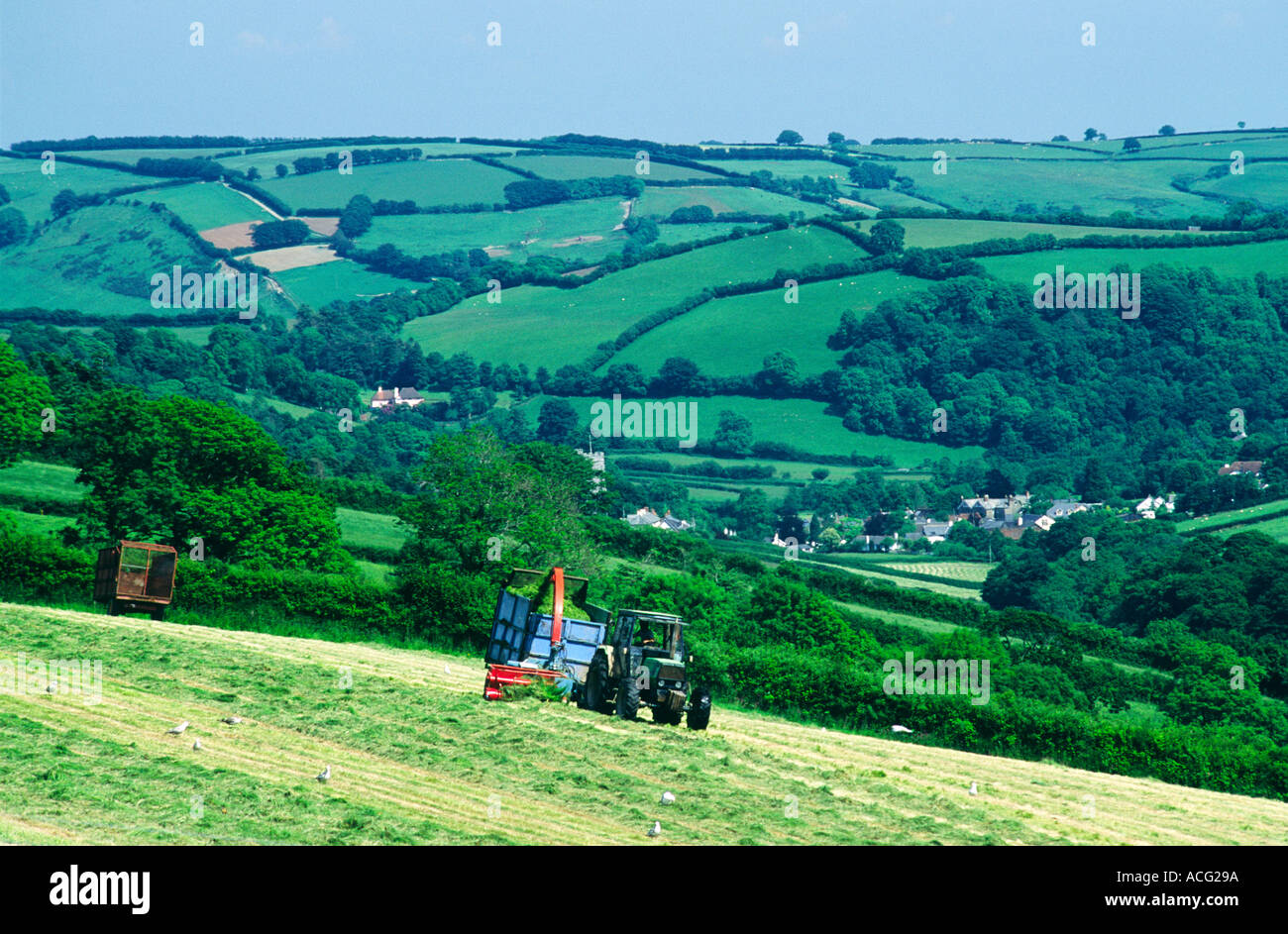 Farmer on tractor cutting grass silage hay in farm field above Winsford ...