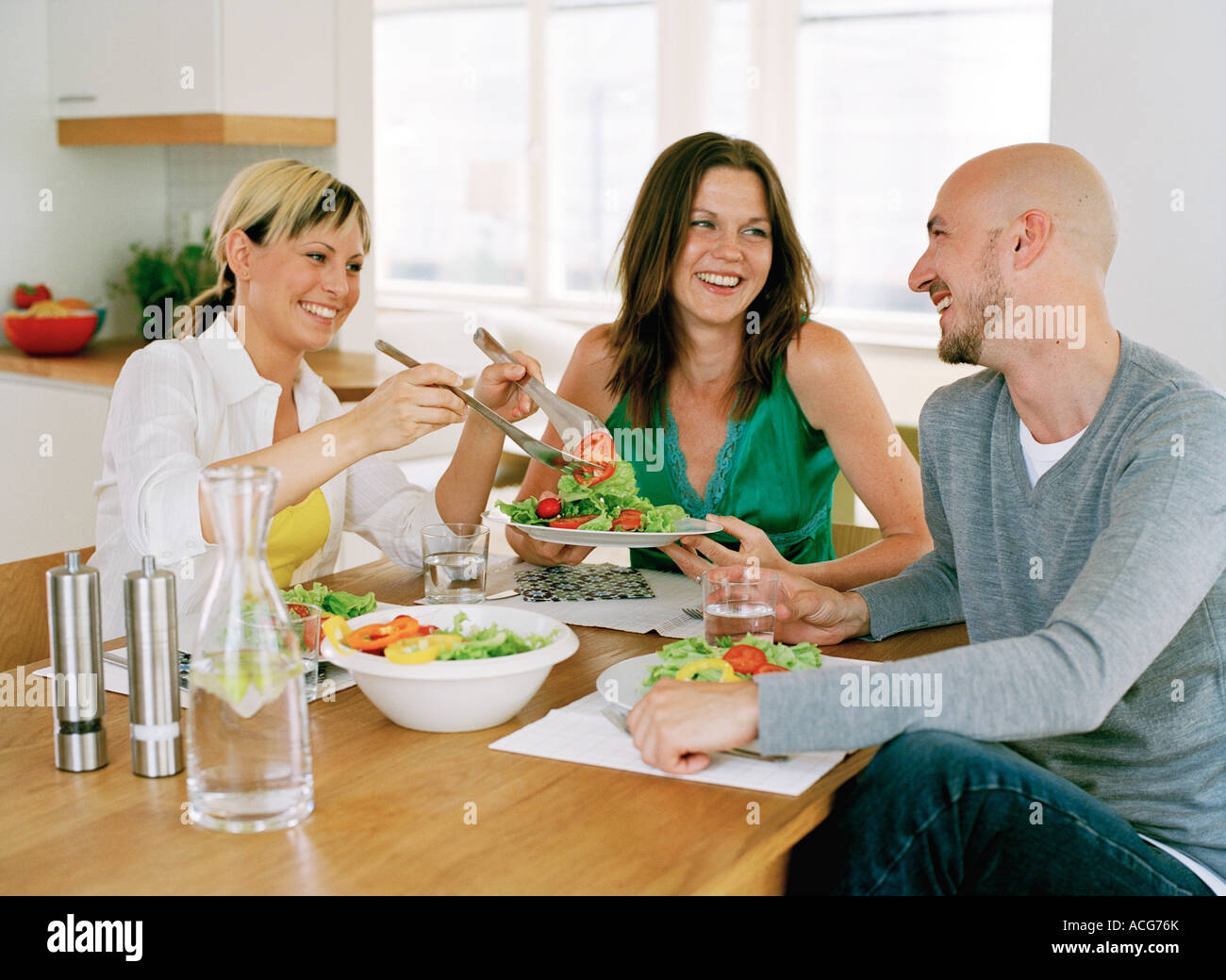 Two women and a man sitting at a table smiling having dinner Stock ...