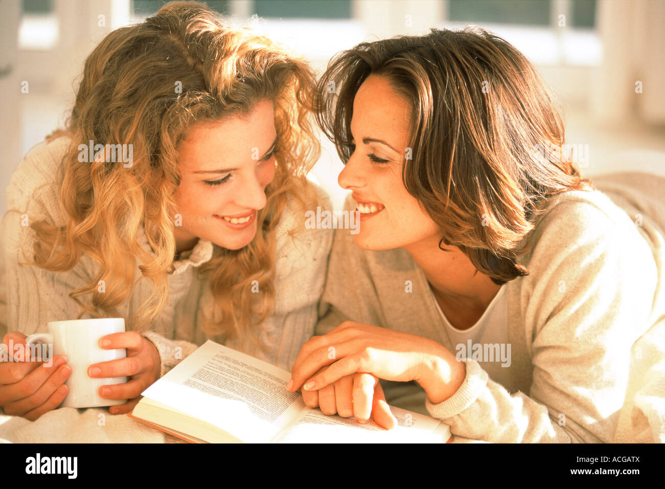 Portrait women smiling lying down on couch book Stock Photo - Alamy