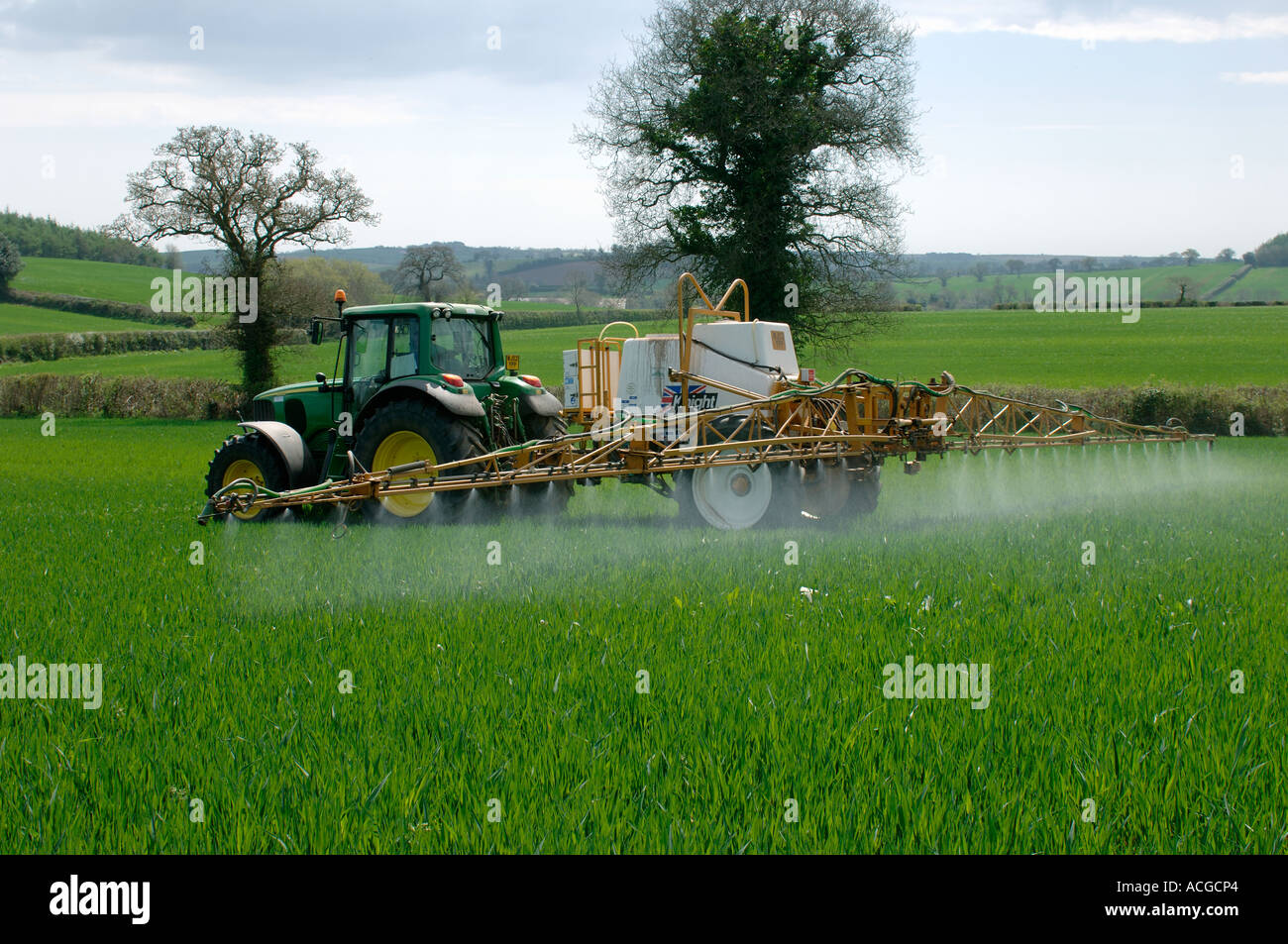 Tractor and trailed sprayer spraying young oats crop in spring Stock ...