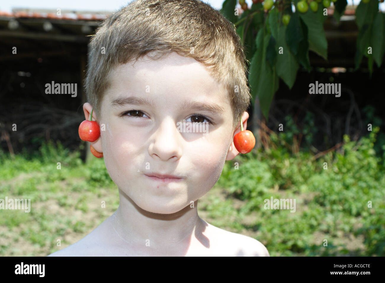 Boy is wearing cherries on his ears Stock Photo - Alamy