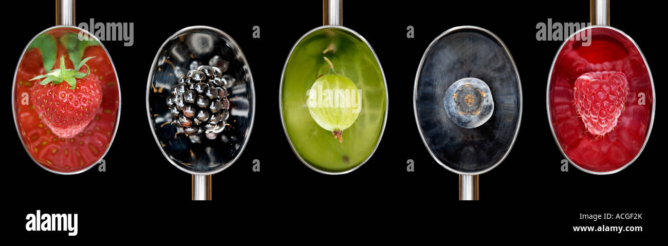 Five assorted fruit berries in scoop spoons against a black background ...