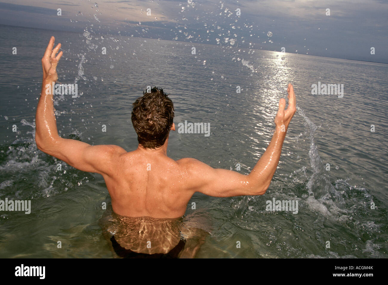 Elevated view on man s back in water hands up splashing Stock Photo - Alamy