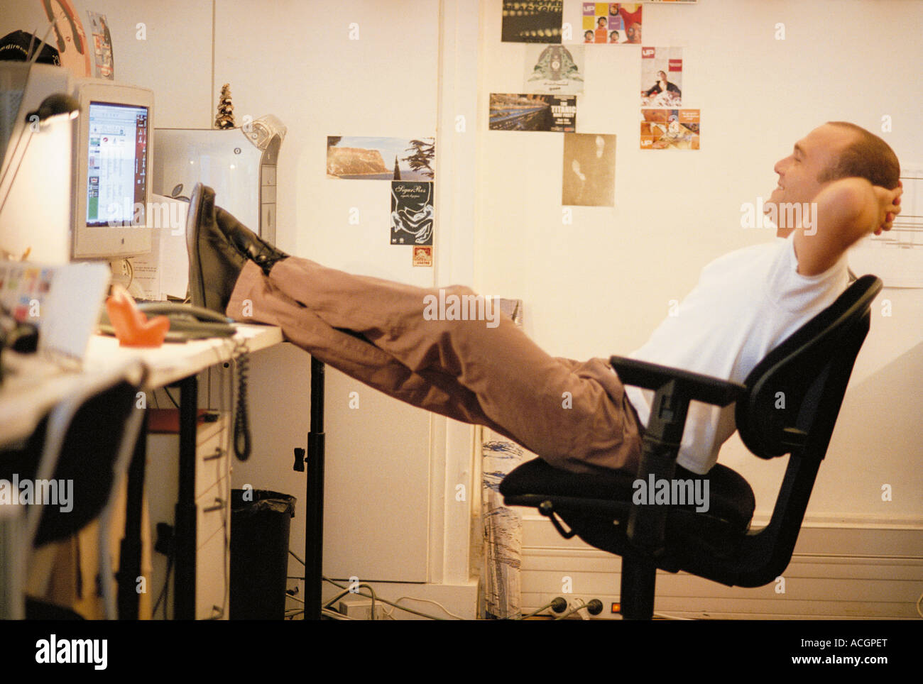 Man sitting on chair feet on desk computer Stock Photo - Alamy