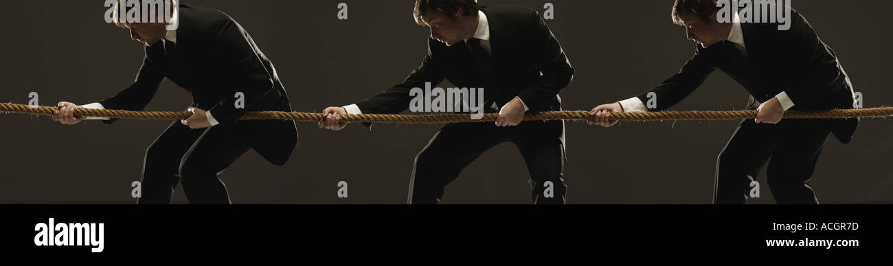 Three men in suits pulling on a rope in a tug o war Stock Photo - Alamy