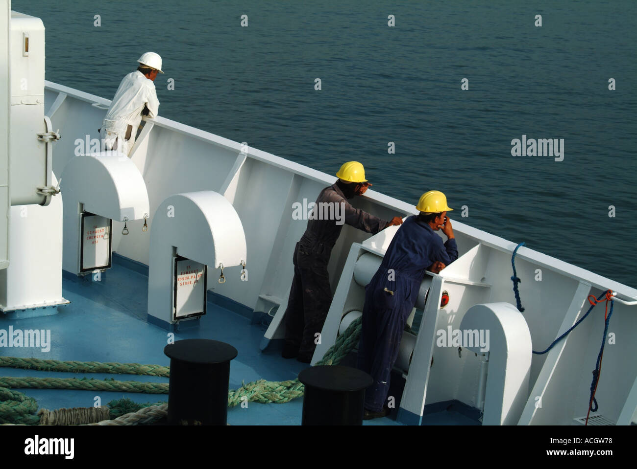 Cruise ship crew awaiting instructions to pass heavy ropes overboard to ...