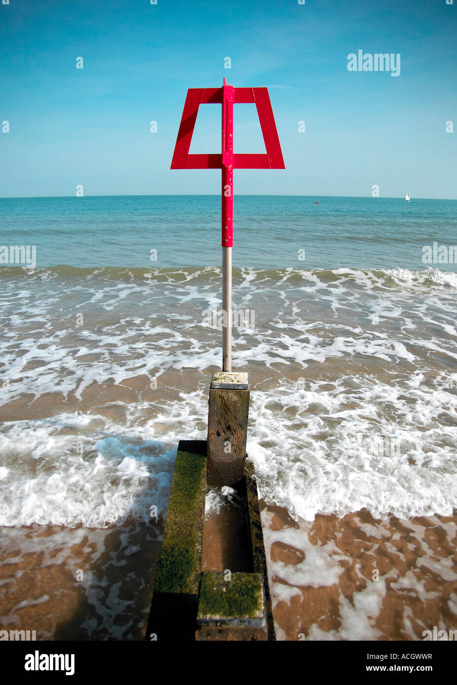 A bright red beach marker situated on a sea defence wall break Stock ...