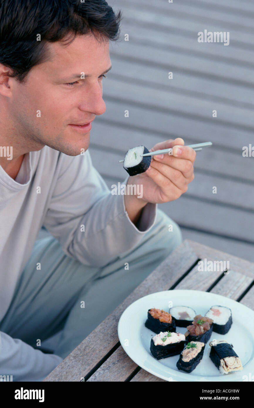 Portrait man sitting cross legged eating sushis with chopsticks Stock ...