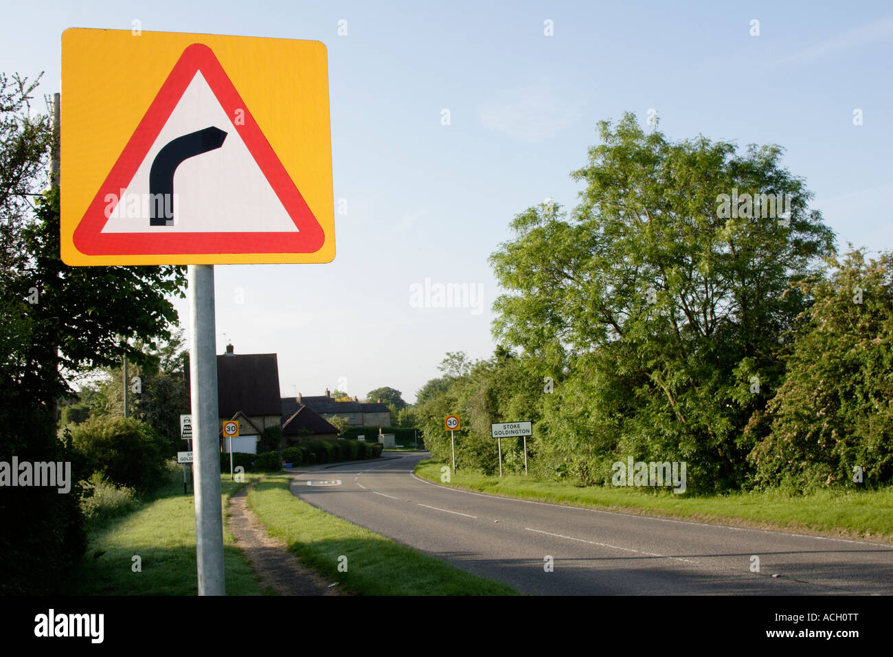 Right hand bend signpost along road entering village, England, UK Stock Photo - Alamy