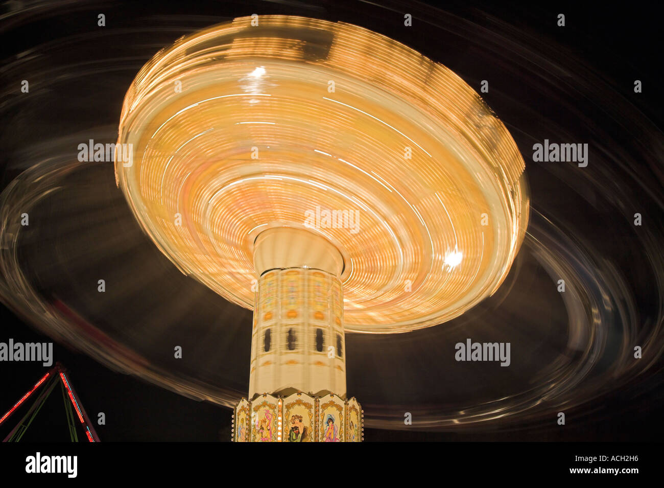 Fast spinning carousel tipping right against black sky Stock Photo - Alamy