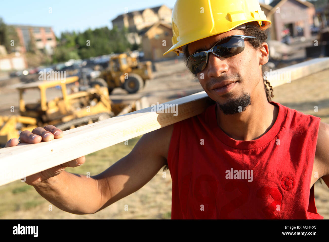 Construction worker with lumber on shoulder Stock Photo - Alamy