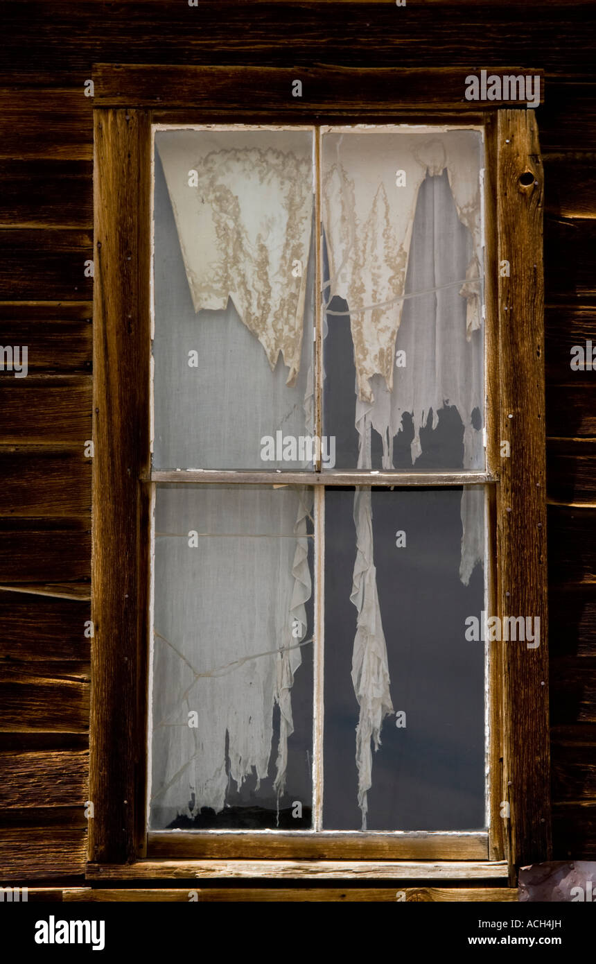 Tattered curtains in window of old house in ghost town of Bodie ...