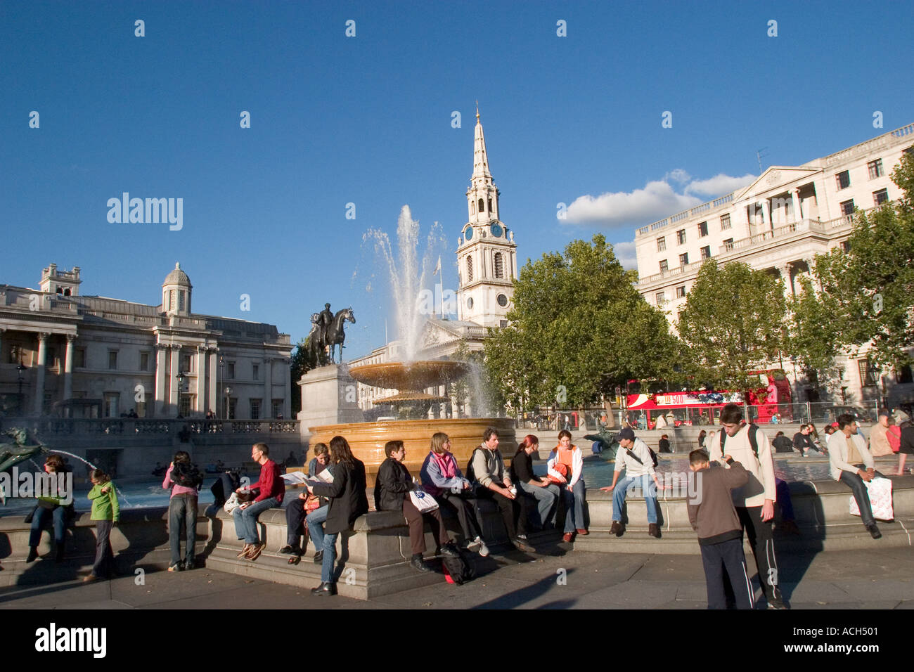 Tourists enjoying the sun and fountains in Trafalgar Square London GB ...
