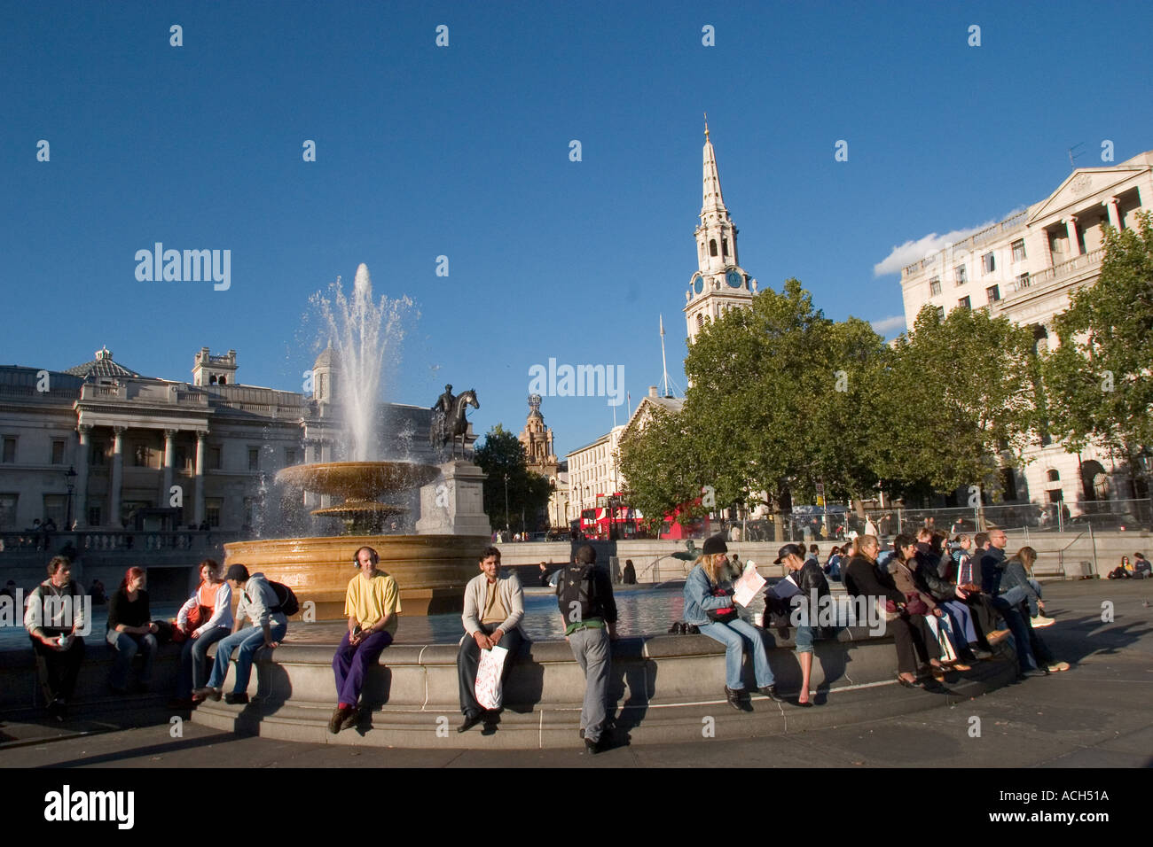 Tourists enjoying the sun and fountains in Trafalgar Square London GB ...