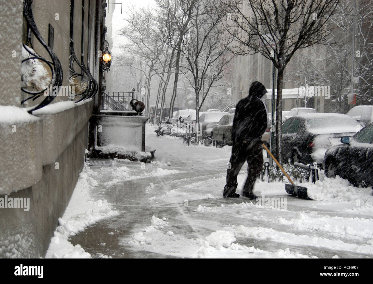 Worker shoveling snow from the sidewalk during a snowstrom New York ...