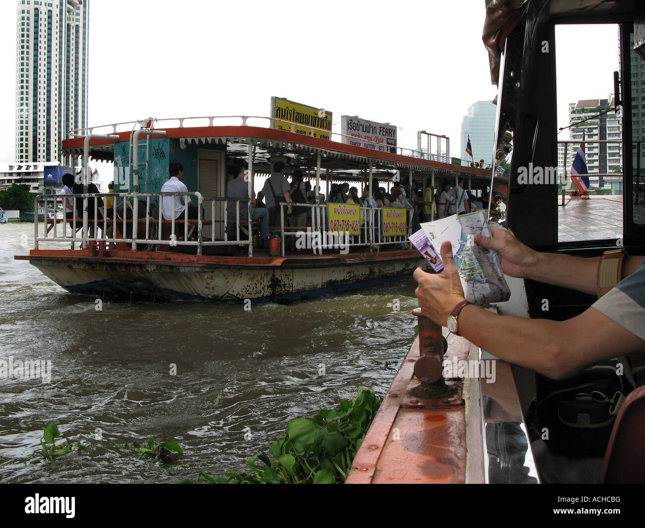 Tourist with a city map on a ferry boat ride on the Chao Phraya River ...