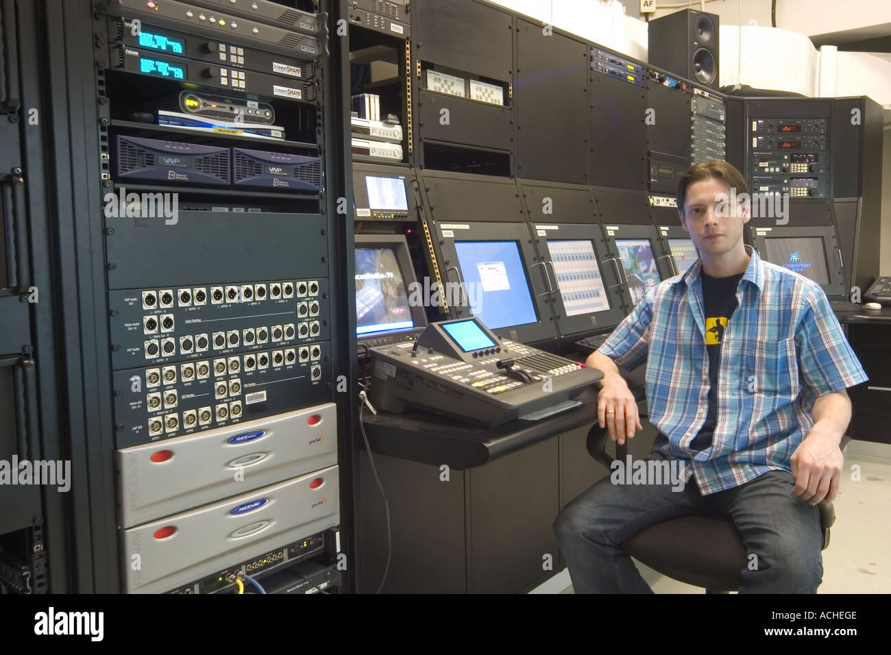 man male sitting at high tech audio visual control deck in AV control ...