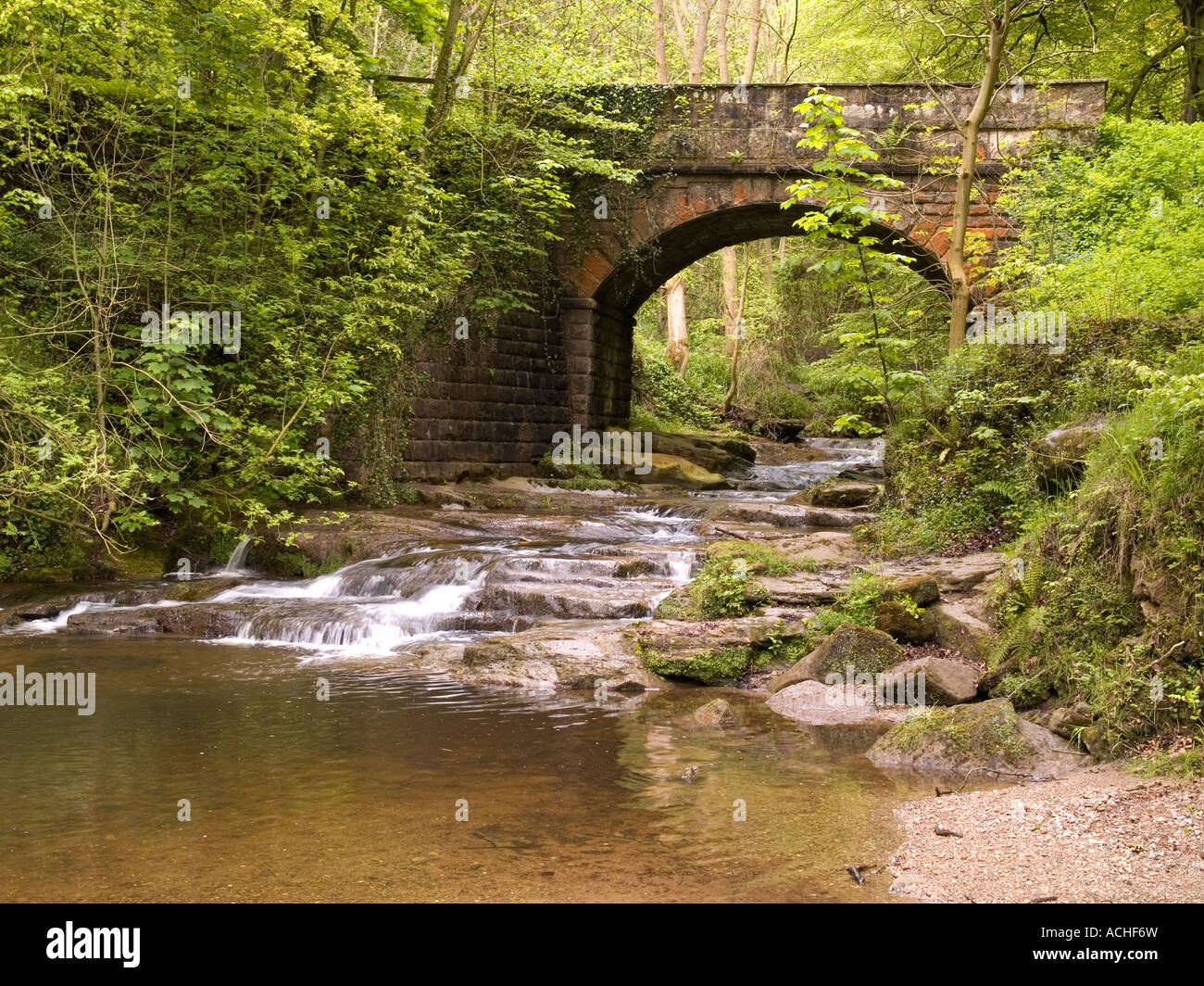 A substantially built stone arch bridge carrying a small track over May ...