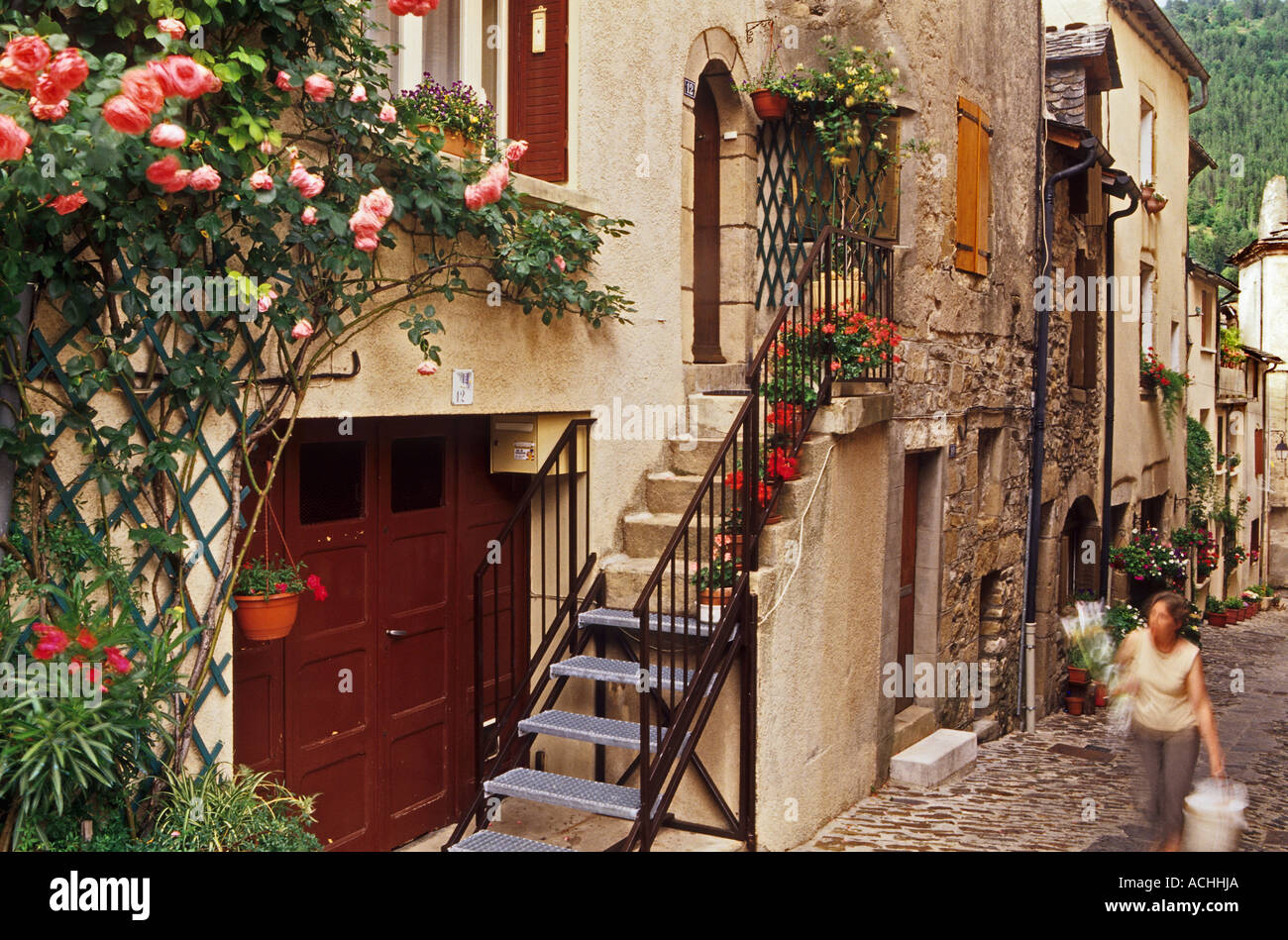 Alley with flowers decorated in the Village of Florac a blurred woman ...