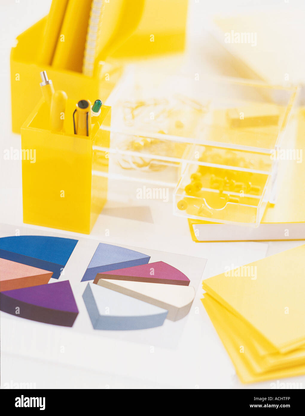 Graph and yellow accessories on desk: post-it pencils paper clips push ...