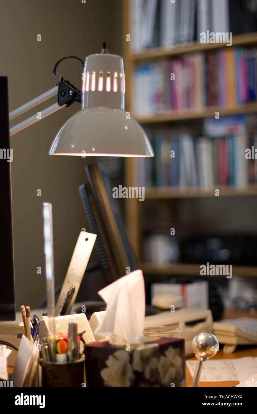 Home office scene with cluttered desk and bookcase illuminated by angle ...