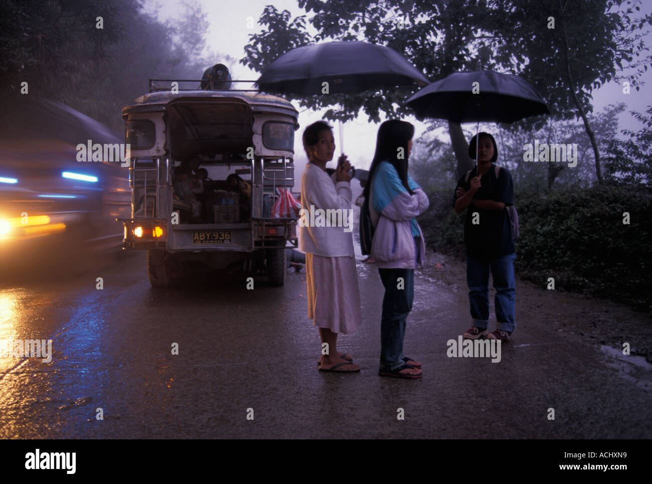 Philippines Woman wait in rain by broken down bus in Banaue Luzon ...