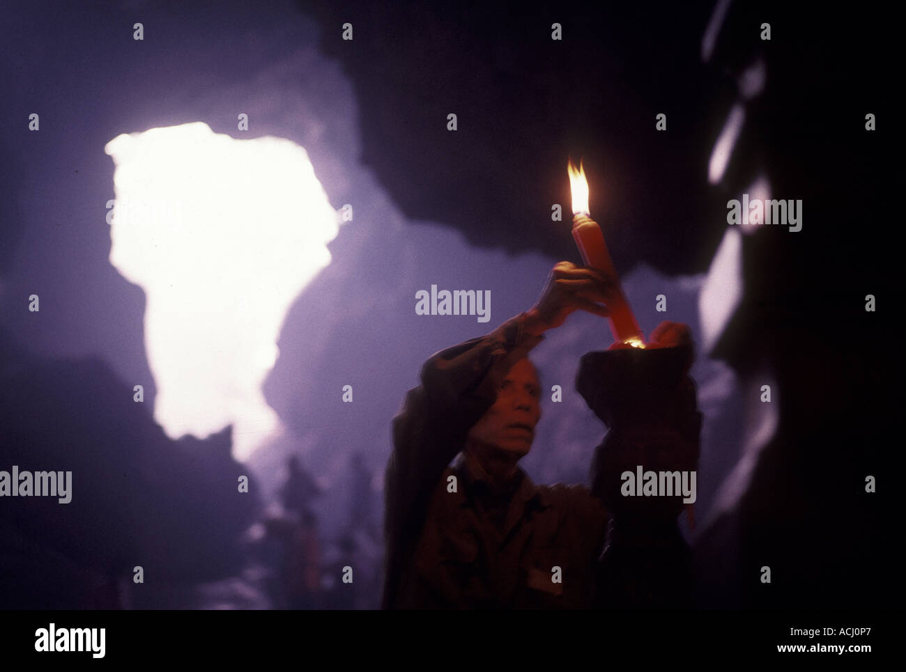 Asia Vietnam Buddhist monk lights candles in limestone cave entrance to ...