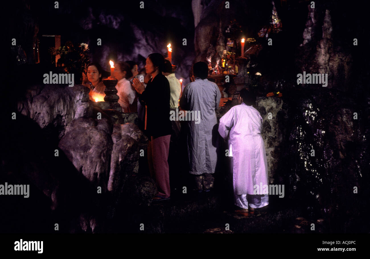 Asia Vietnam Woman prays at alter by candle light in limestone cave at ...