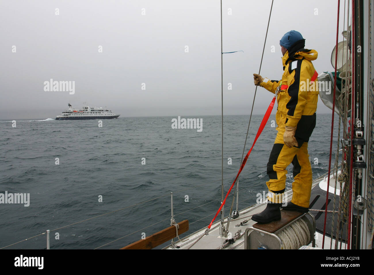 Antarctica Crew member watches passing cruise ship from deck of S V ...