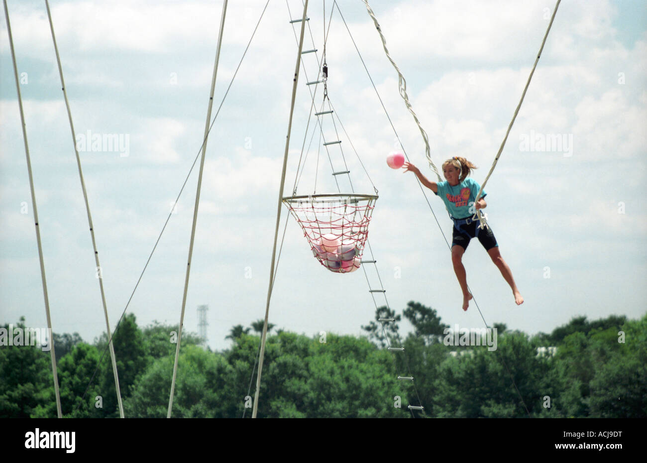 Woman in a bungee harness throwing balls into a net Stock Photo - Alamy