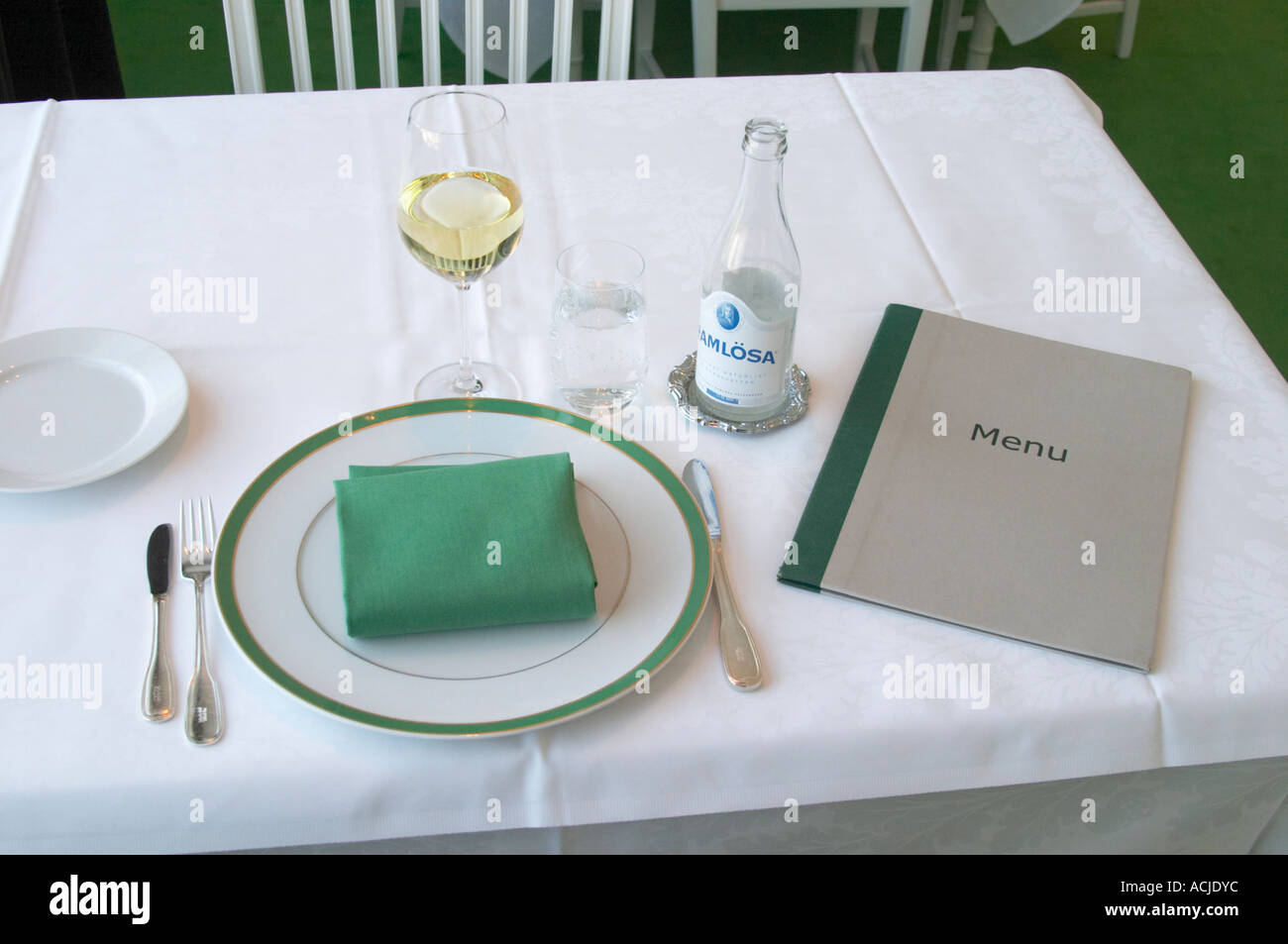 A restaurant table with a white linen table cloth set for one person ...