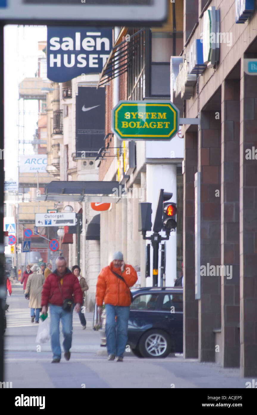 A busy street in Stockholm with publicity signs for shops and a sign ...