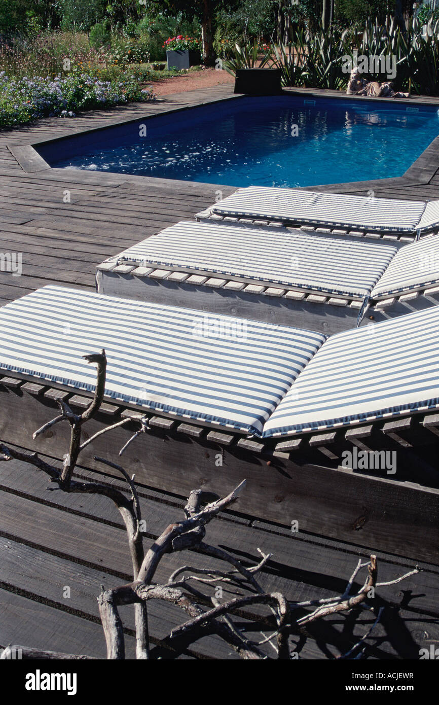 3 striped deckchairs in wooden terrace swimming pool flowery garden ...